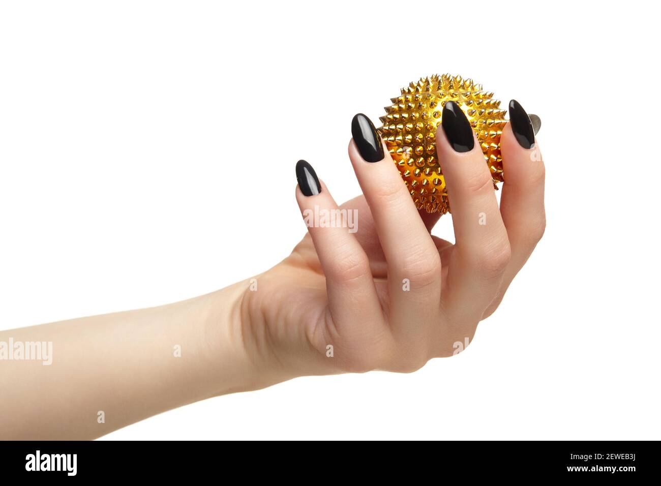Female hand with black nails manicure and golden spiked massage ball in ...