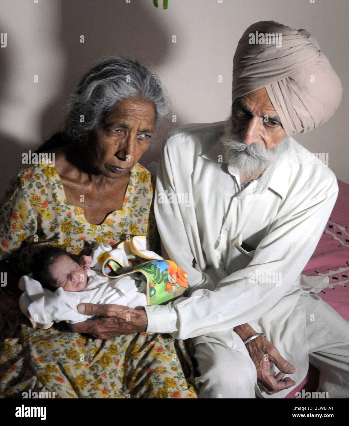 Mohinder Singh Gill, 79 (R) and his wife Daljinder Kaur, 70, pose for a photo holding their ...