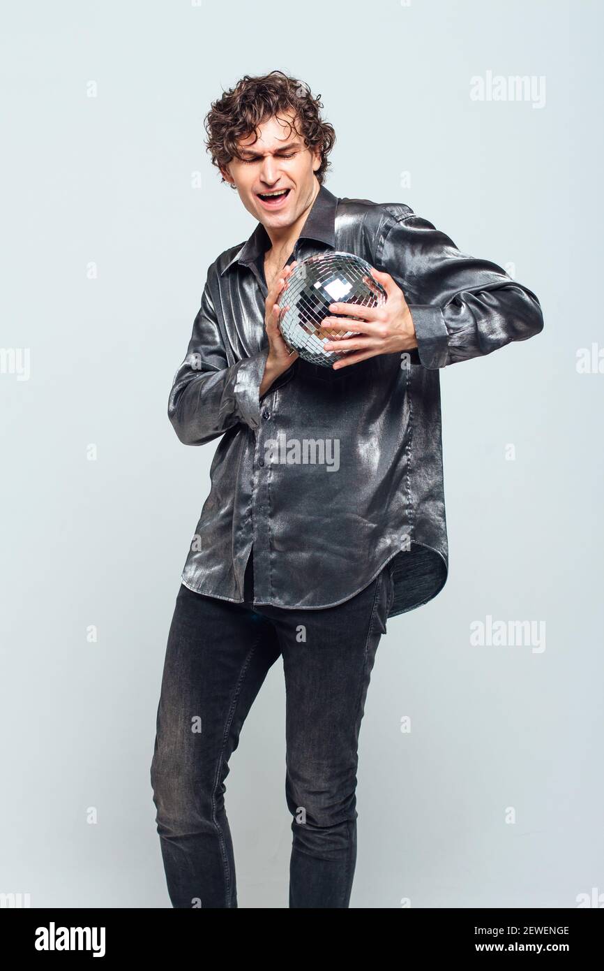 Handsome man posing with a shiny disco ball in studio Stock Photo - Alamy
