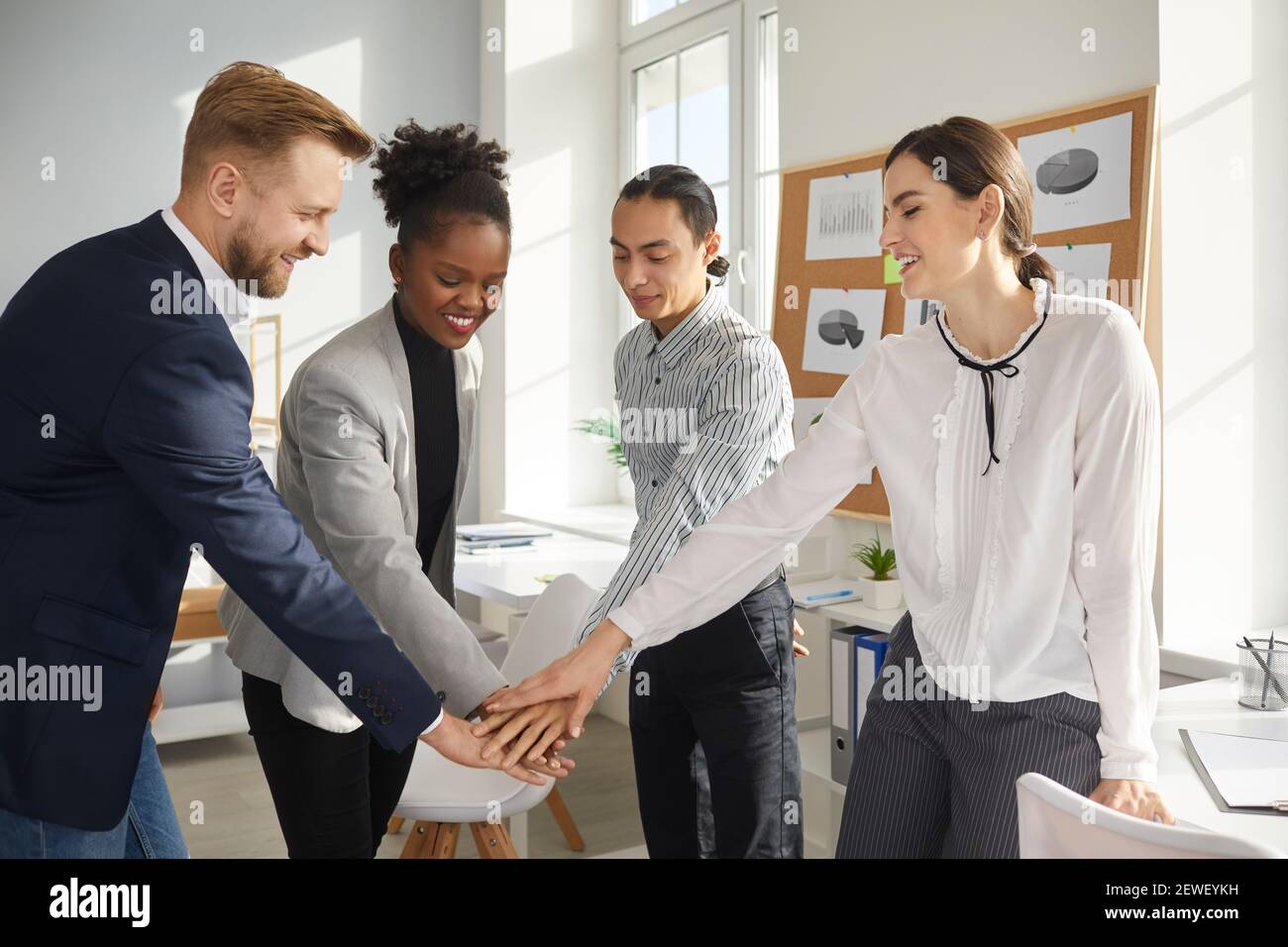 Multiracial colleagues fold their hands on each other as a symbol of ...