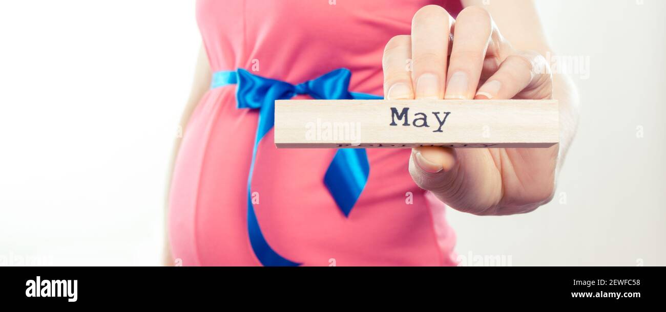Woman in pregnant wearing pink dress with blue ribbon and showing word ...