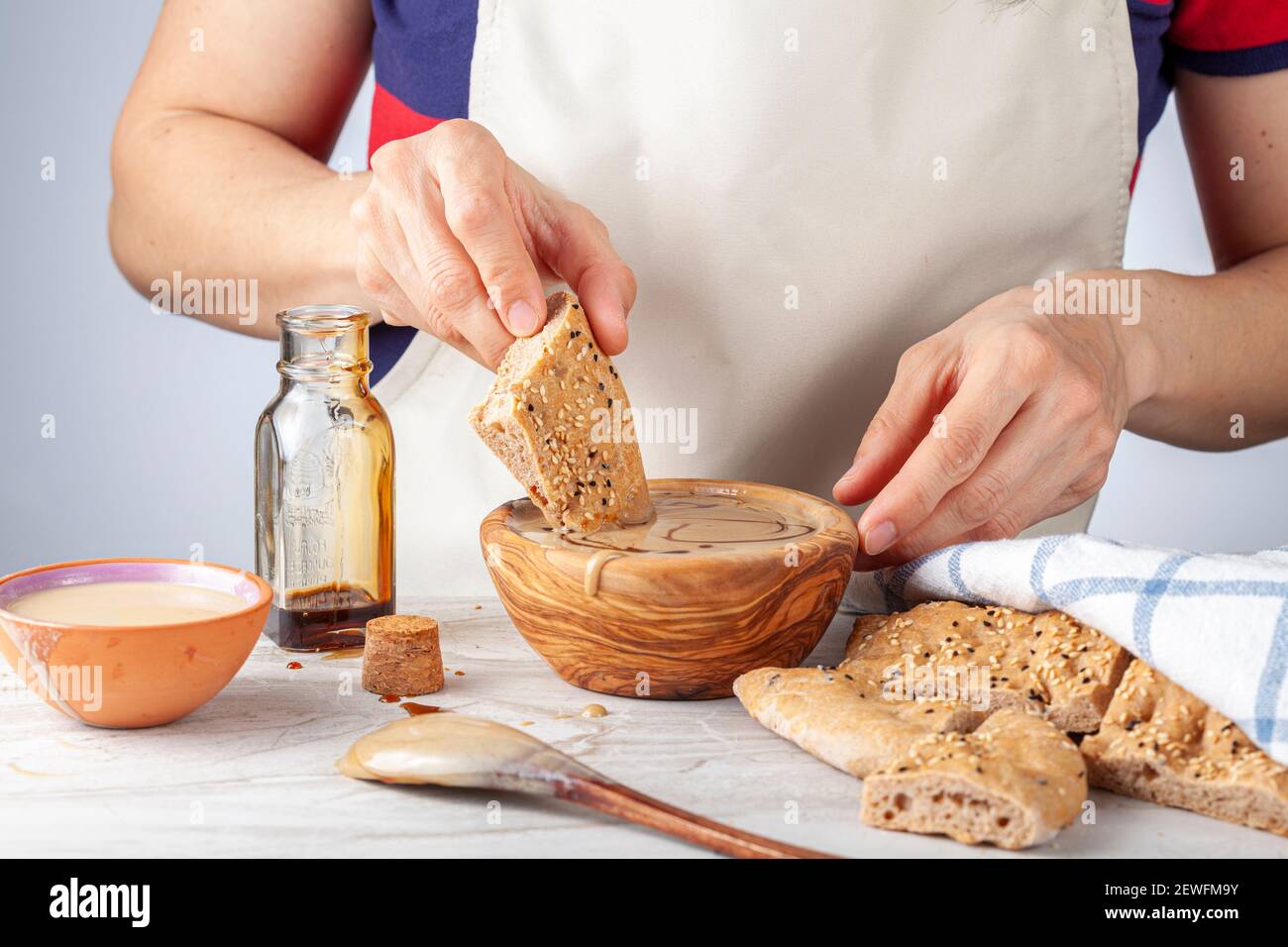 A caucasian woman wearing apron is dipping turkish pide (flat bread ...