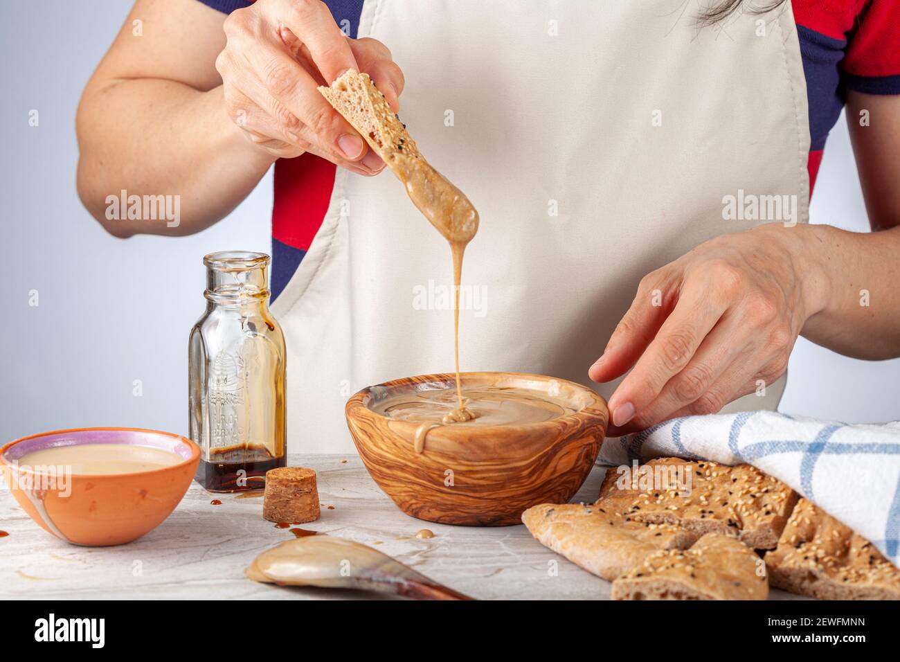 A caucasian woman wearing apron is dipping turkish pide (flat bread ...