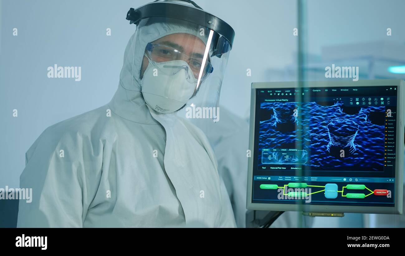 Microbiologist in ppe suit standing in laboratory looking at camera ...