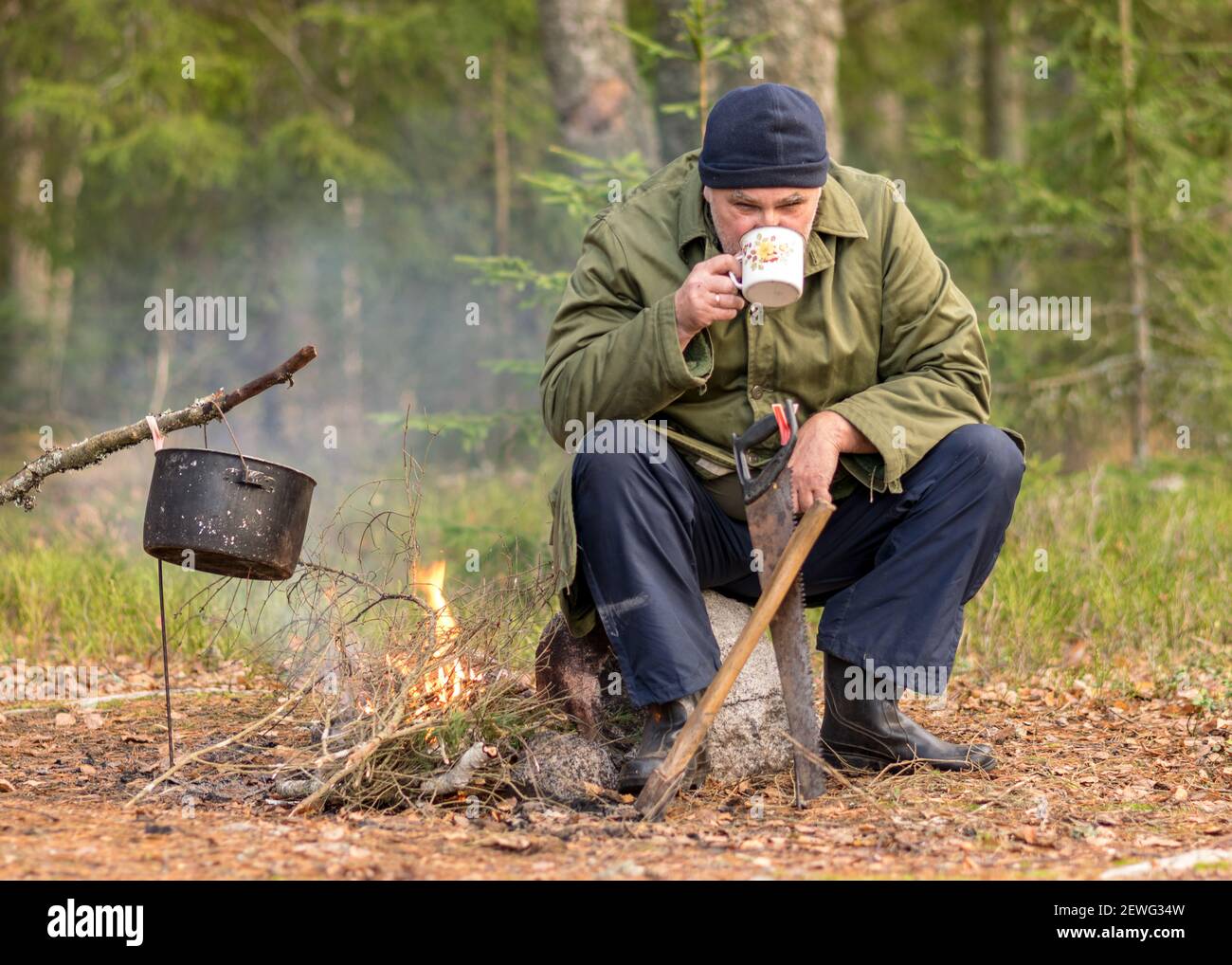 a forester in the forest drinks tea at rest, blurred forest background ...