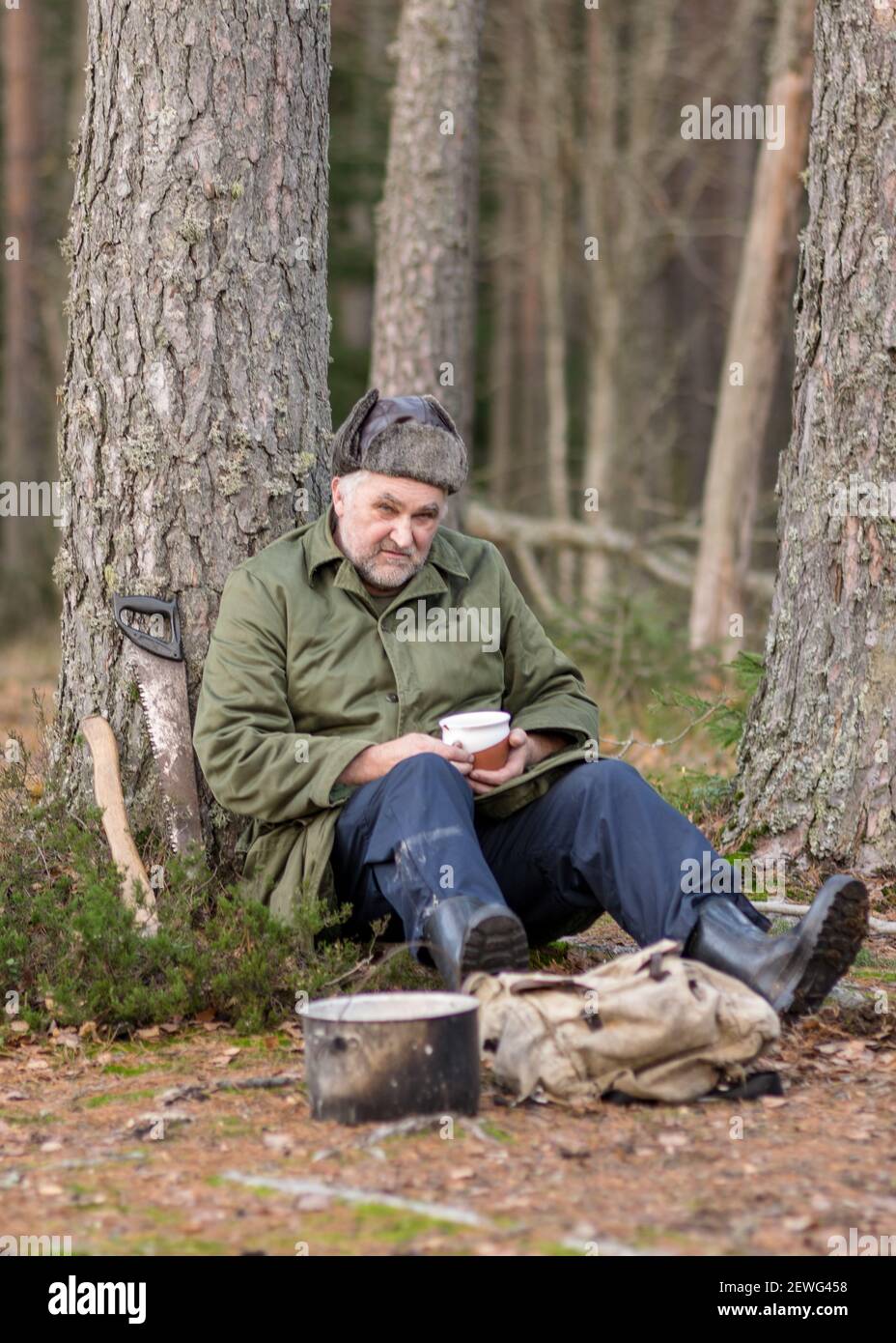 a forester in the forest drinks tea at rest, blurred forest background ...