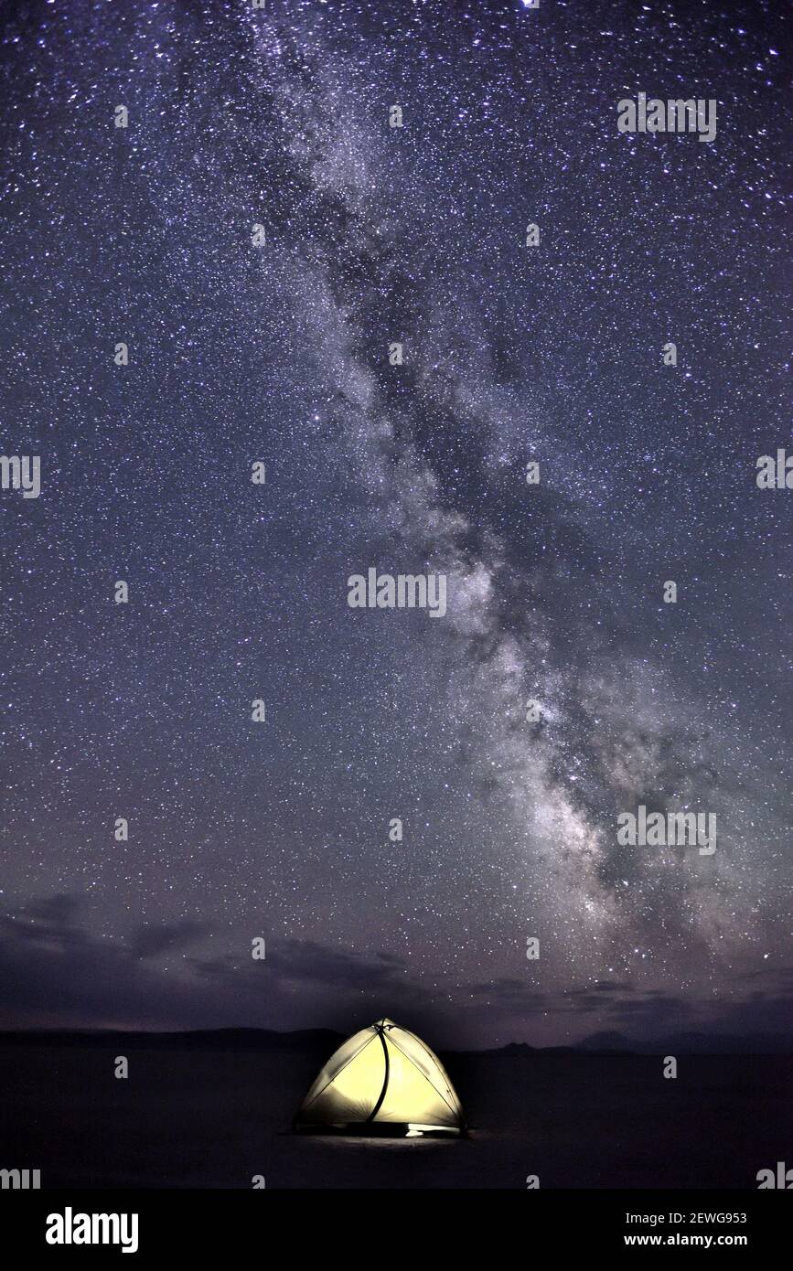 The Milky Way glows above an illuminated tent on the Alvord Desert near ...
