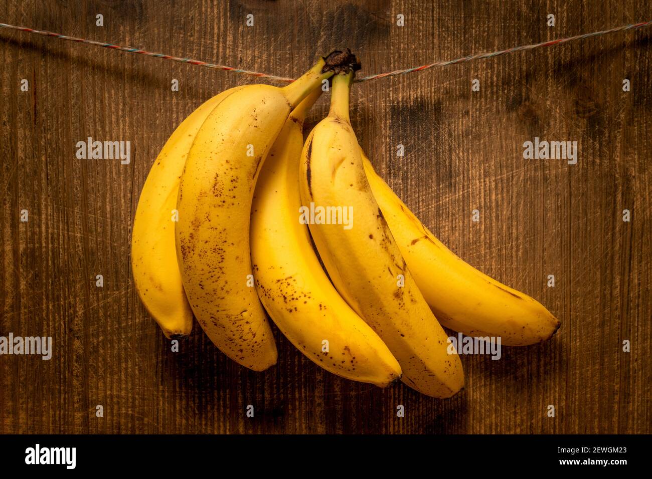 The banana bunch hanging on the rope over a wooden background Stock ...