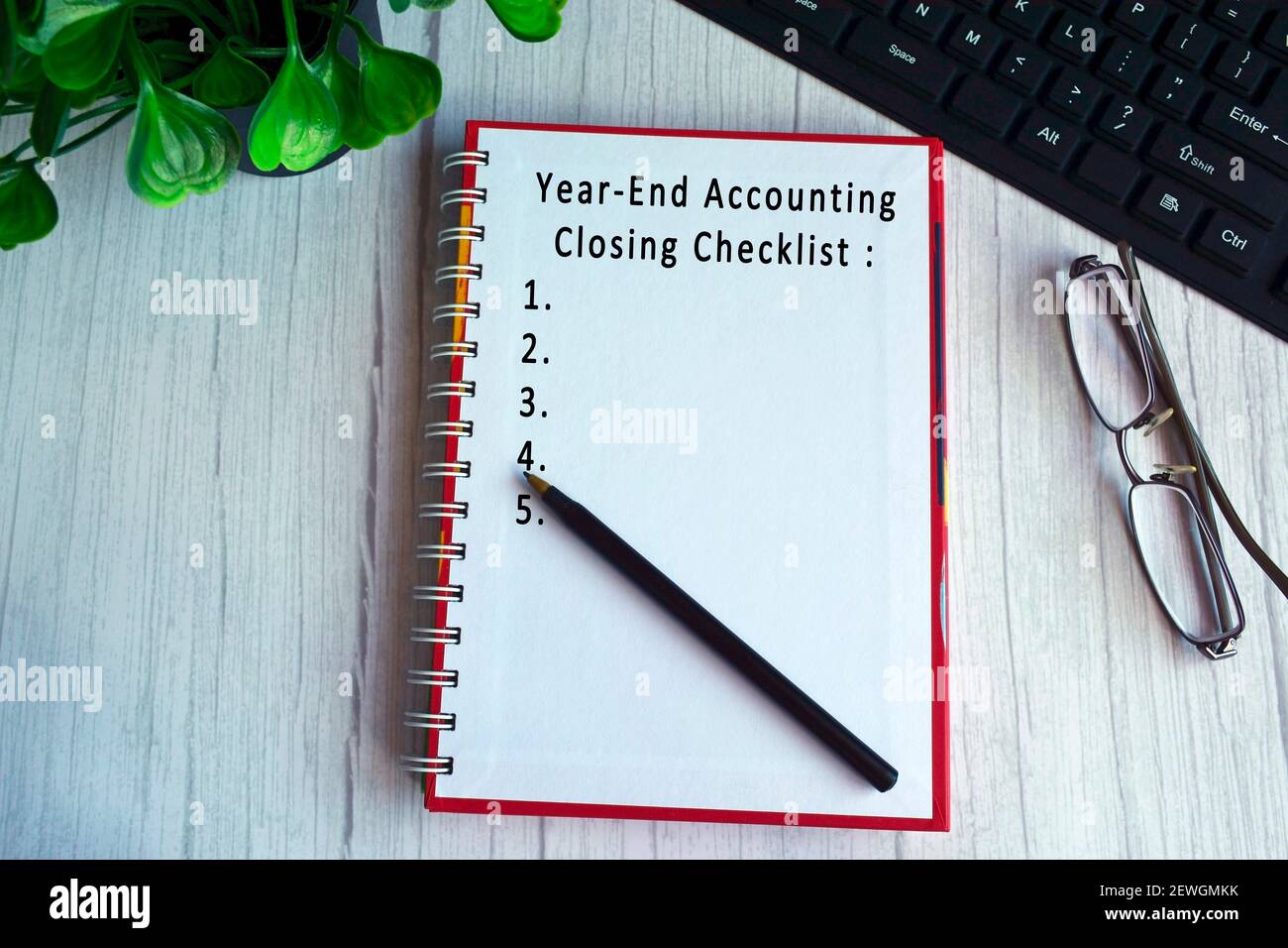Text on notebook with glasses, pen, keyboard and green plant on the table - Year end accounting ...
