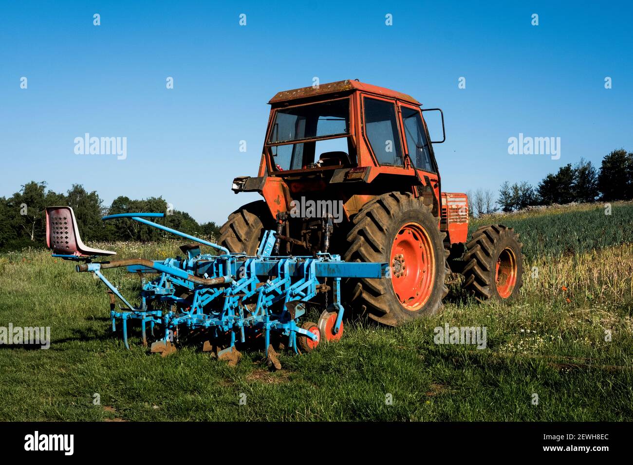 Red tractor with blue harrow on a farm Stock Photo - Alamy