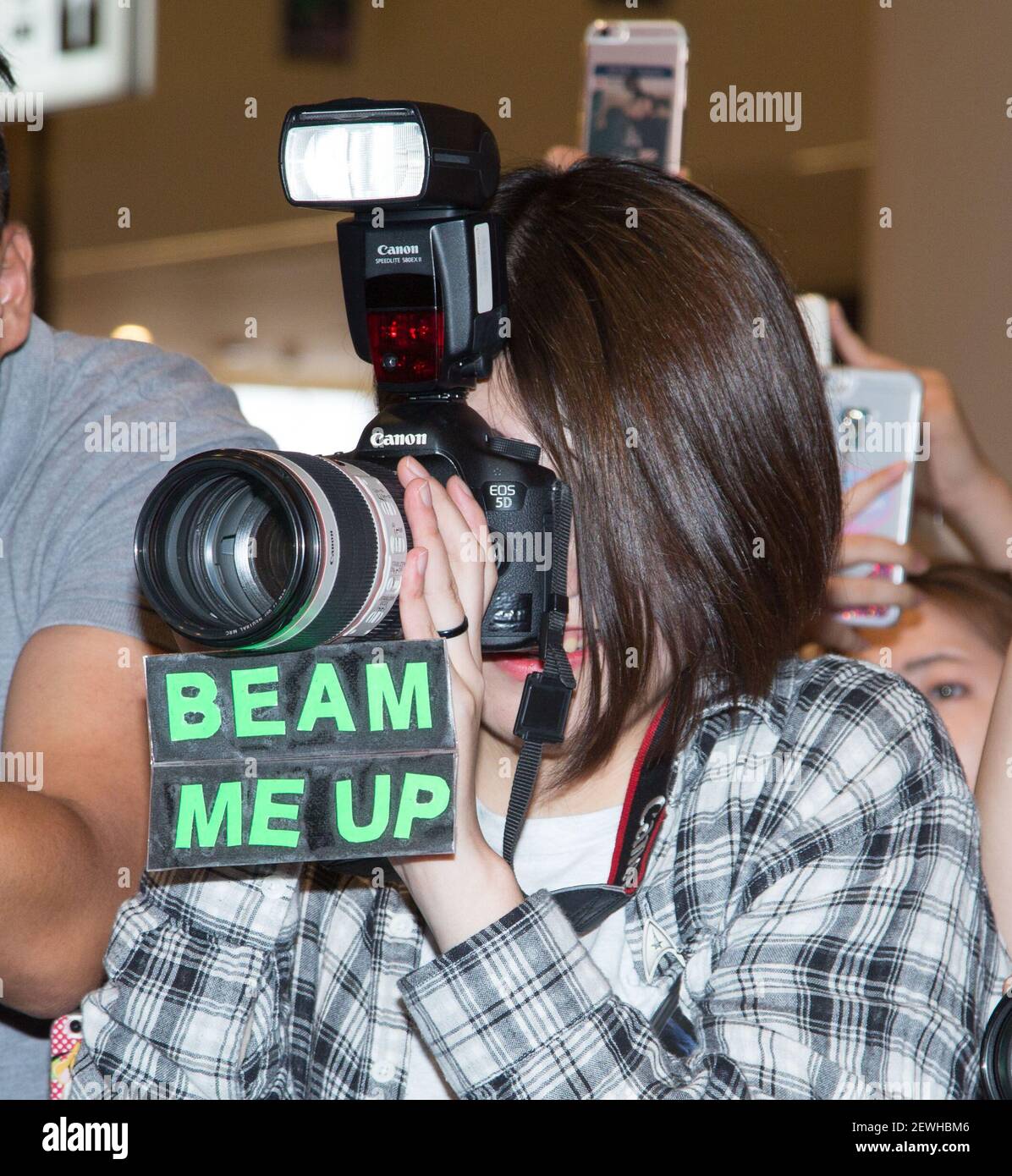A photographer with a sign that reads "Beam Me Up" at the red carpet ...