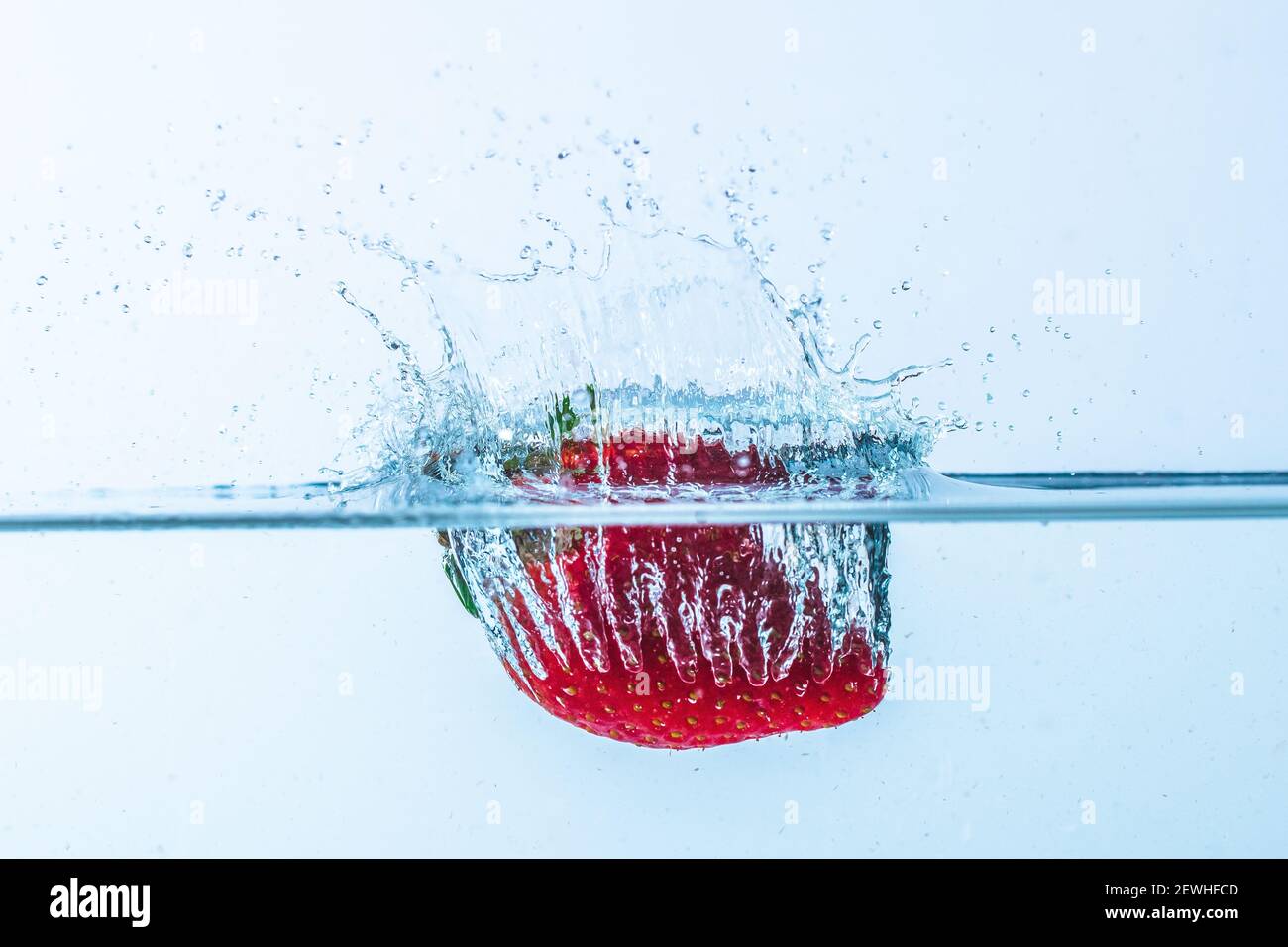 A strawberry falling into water with a splash Stock Photo - Alamy