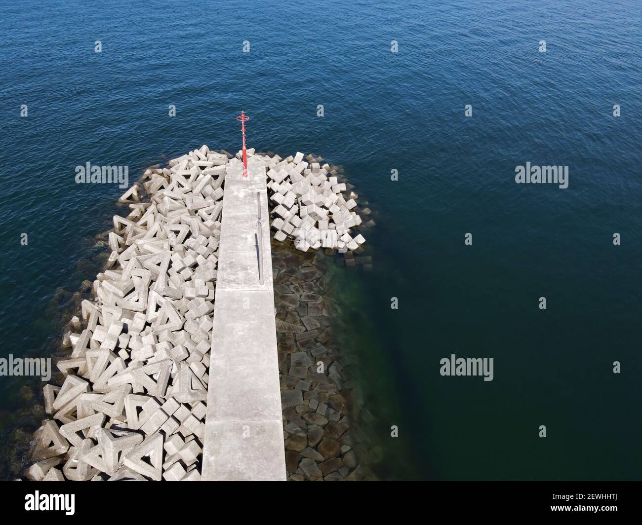 Aerial view of jetty with concrete blocks, white jetty against blue ...
