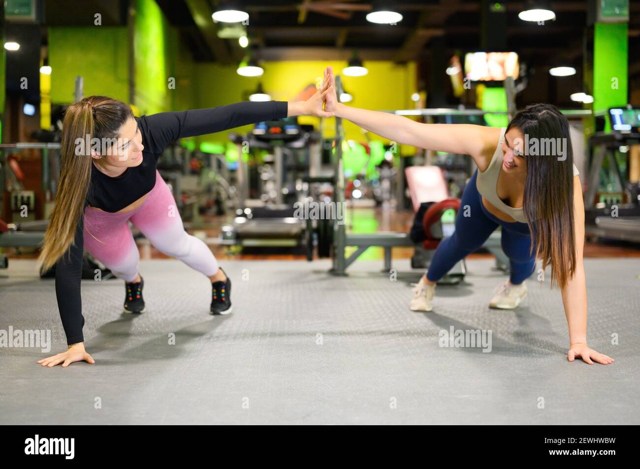 Two sporty women doing high five while workout push up exercise in Gym ...
