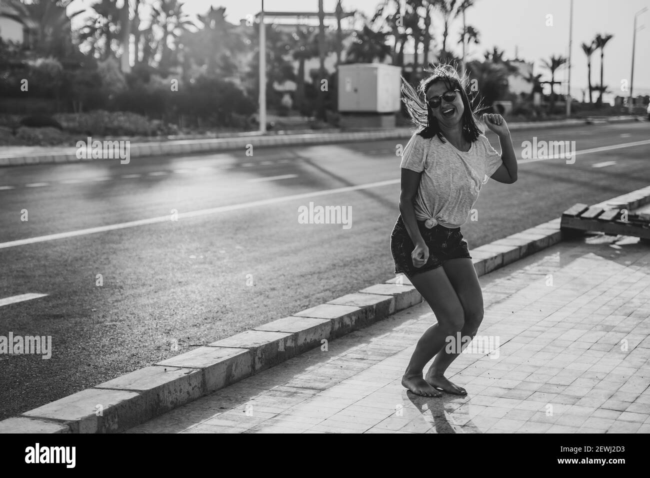 Black and white photo of a young girl in shorts in a jump in the summer ...
