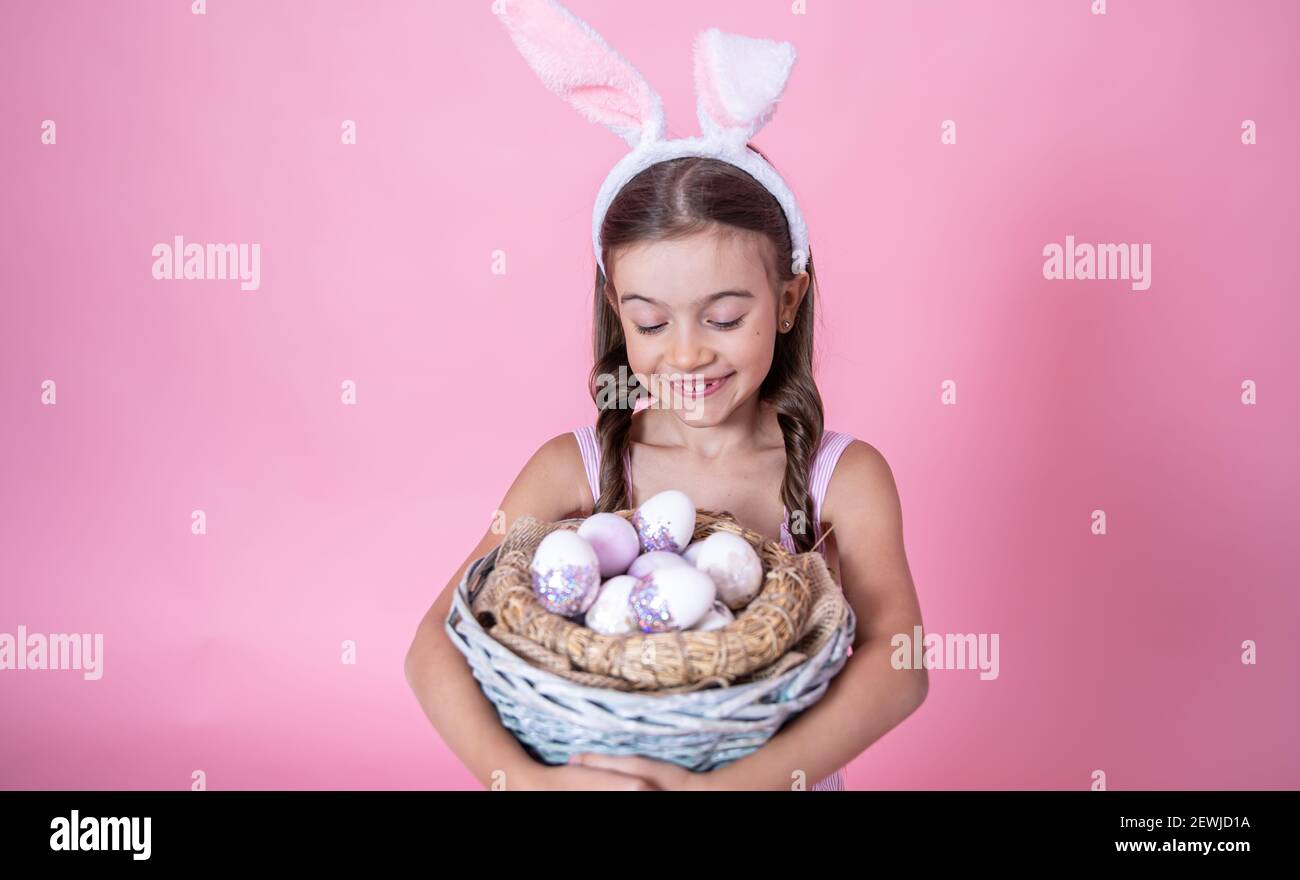 Little girl with Easter bunny ears posing holding a basket with festive ...