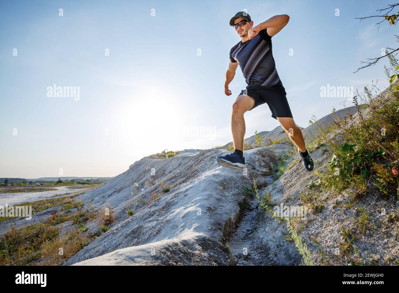 young fit man jumping on his trail running on hill Stock Photo - Alamy