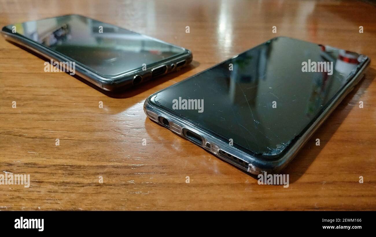 A selective focus shot of two black smartphones with damaged screen ...