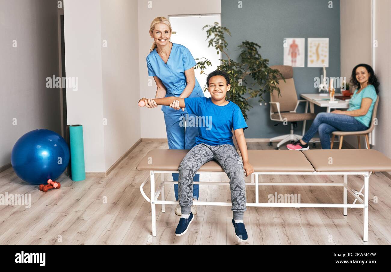 Therapist treats injured hand of African American child patient with ...