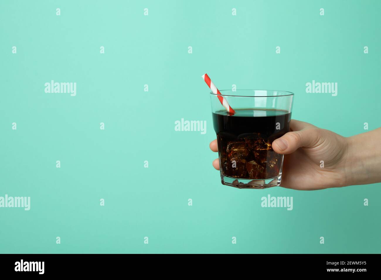 Female hand hold glass of cola on mint background Stock Photo - Alamy