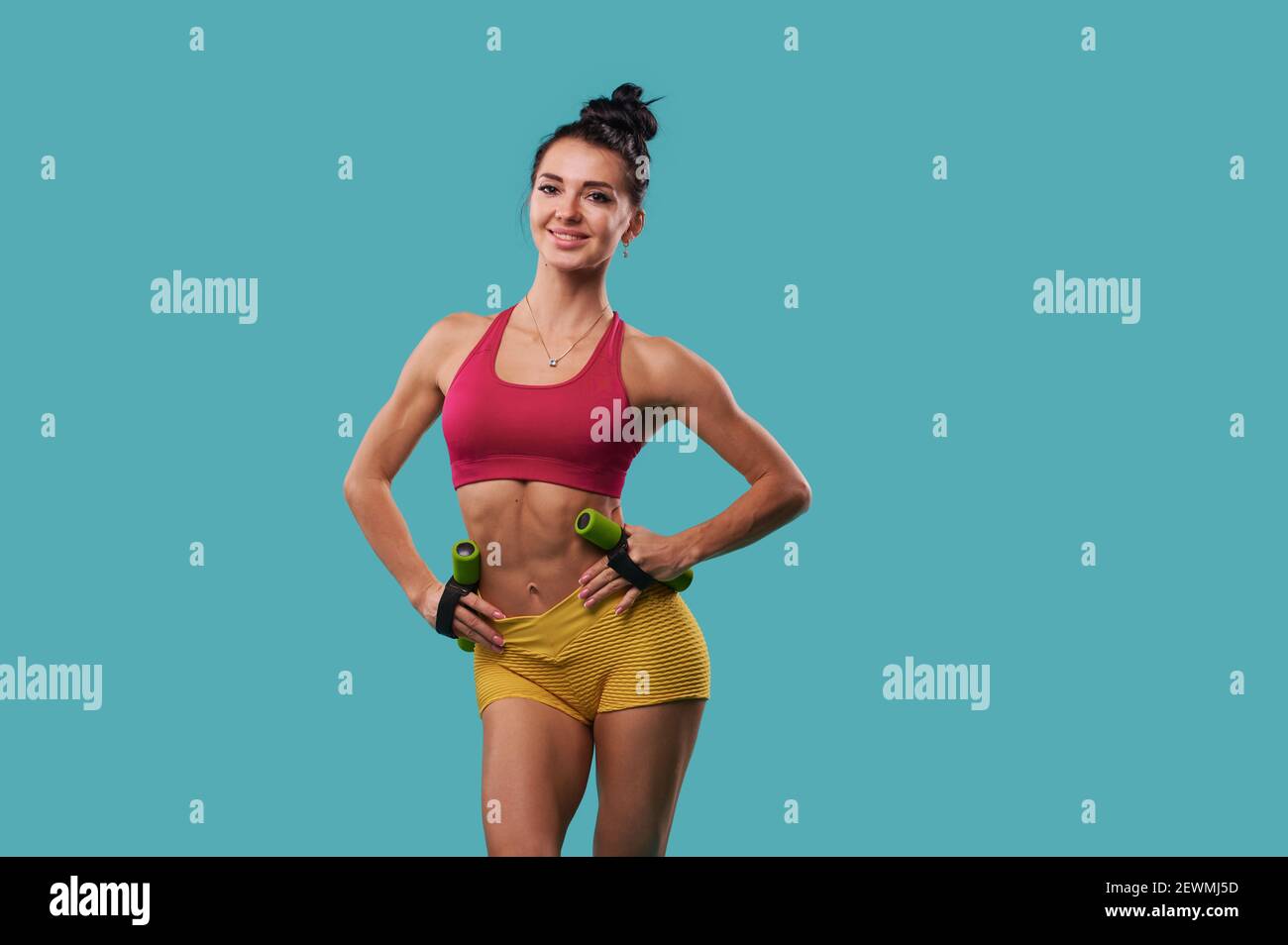 Muscular build fit woman poses for the camera with dumbbells in her ...