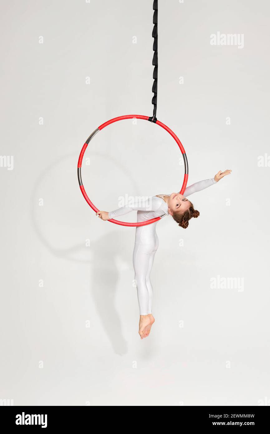 cute child girl gymnast in white sportwear shows an acrobatic ...
