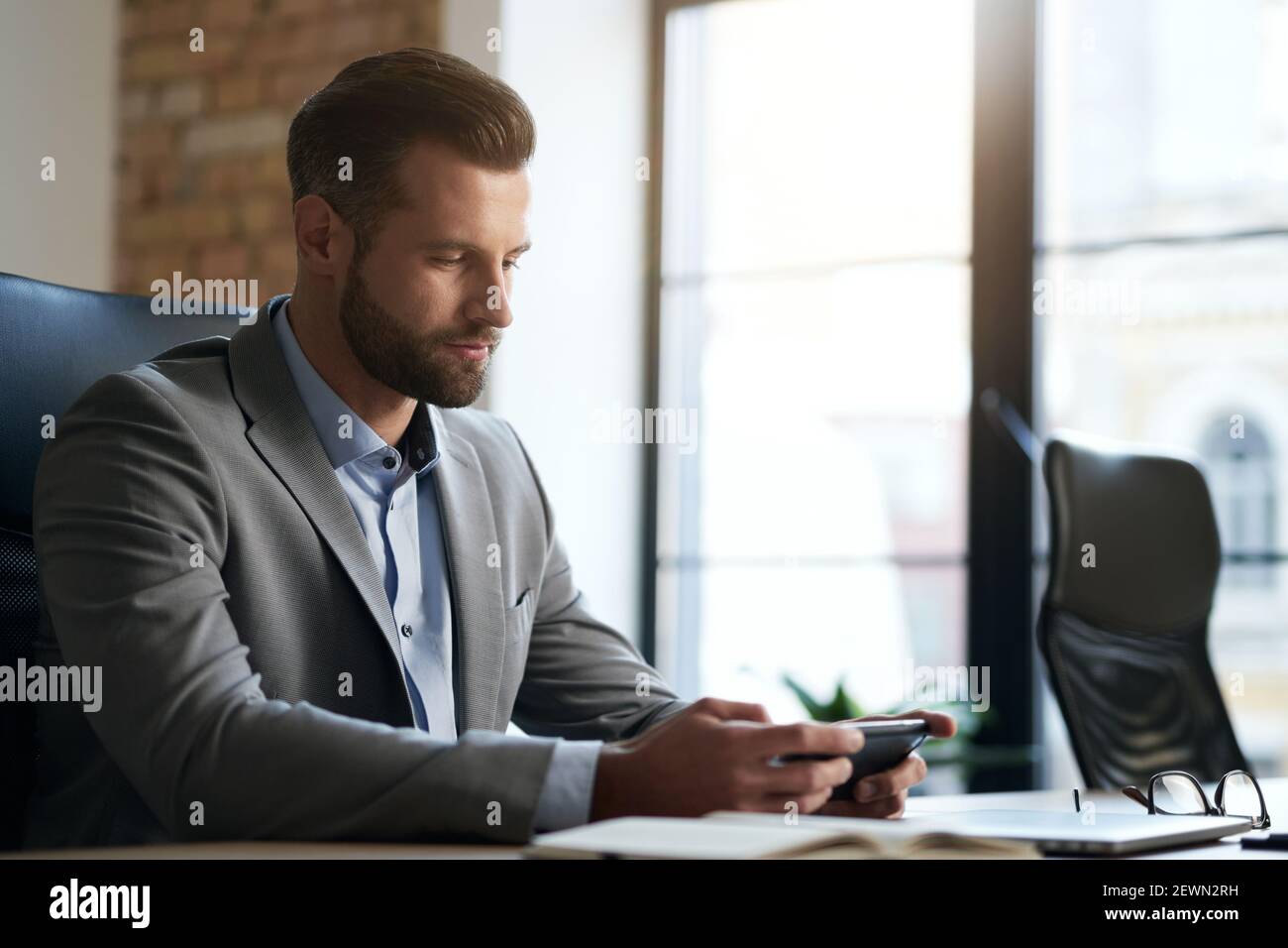 Handsome Caucasian young man in a grey suit sitting at the table and ...