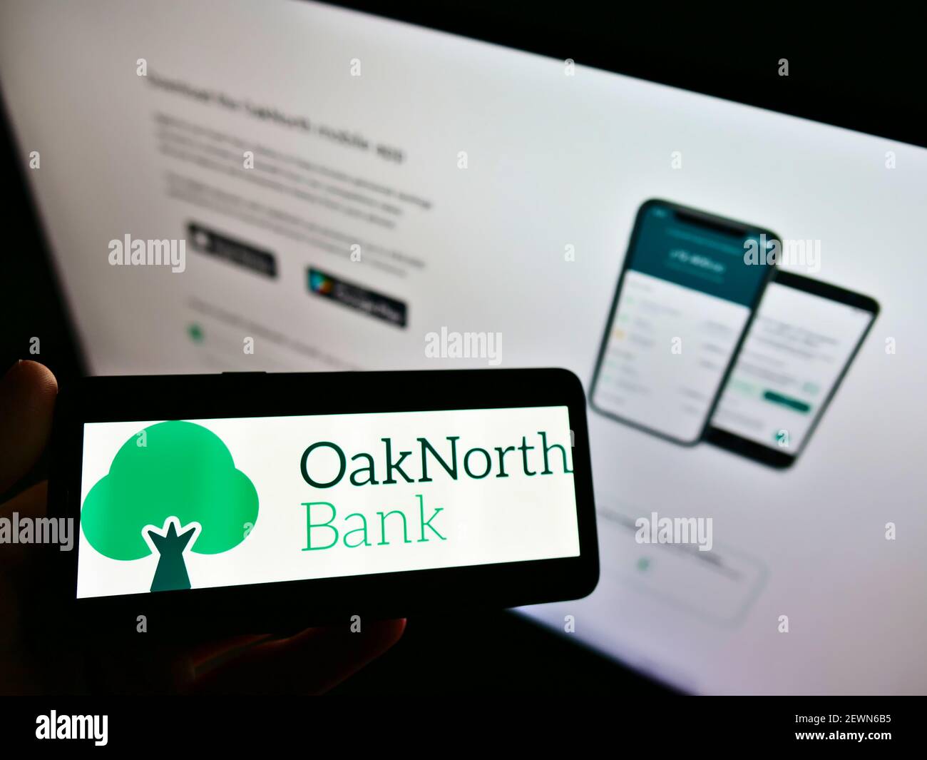 Person holding cellphone with logo of British financial company OakNorth Bank plc on screen in ...