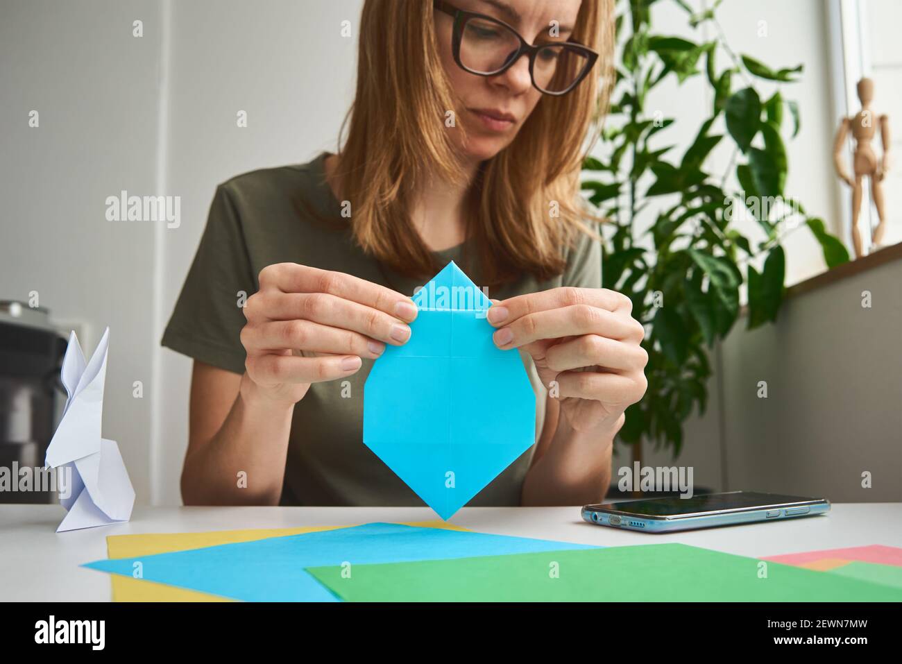 Origami lessons. Woman make origami easter rabbit from color paper. DIY ...