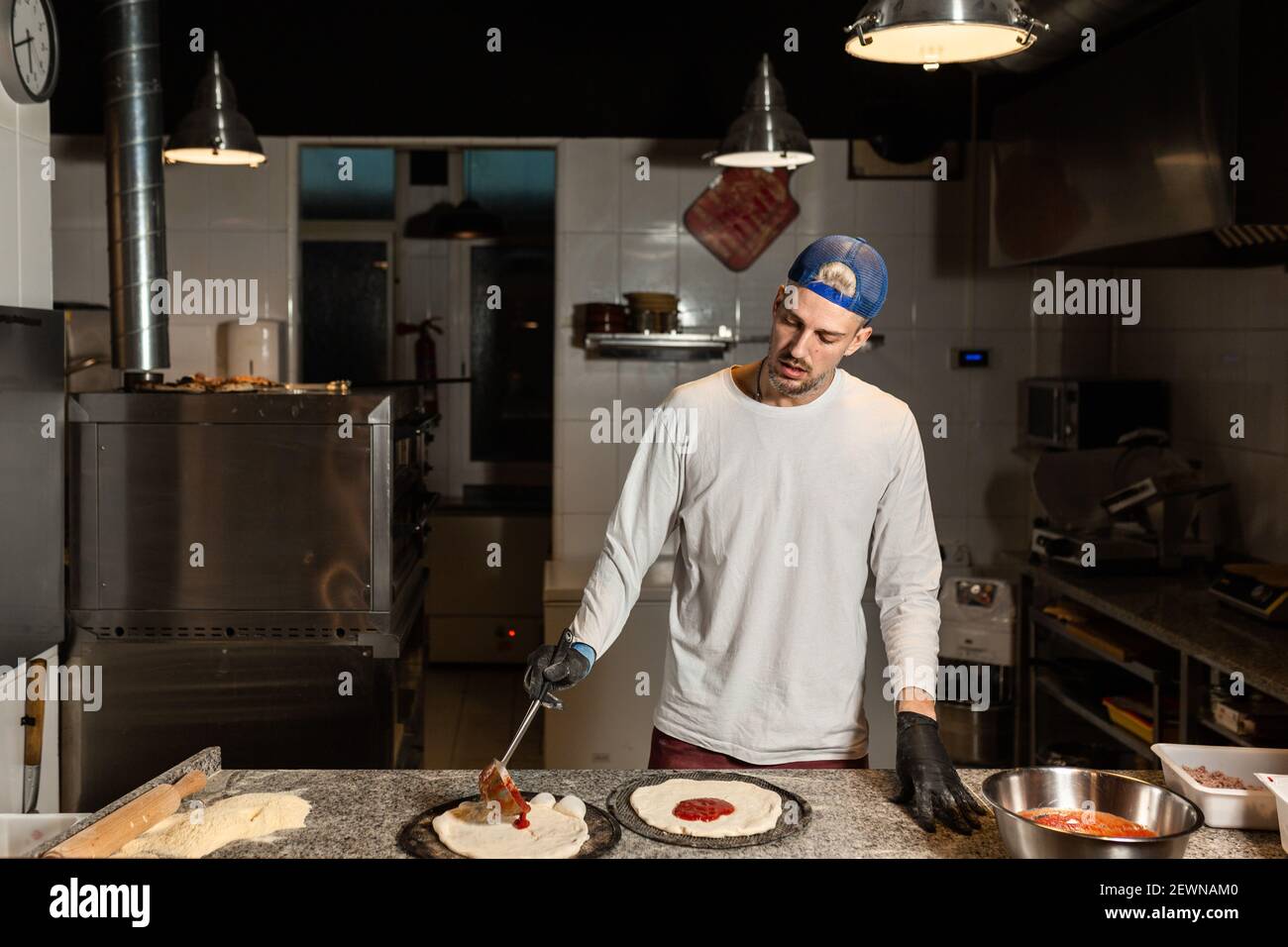 pizza man adds tomato to a pizza in a pizzeria restaurant kitchen Stock ...
