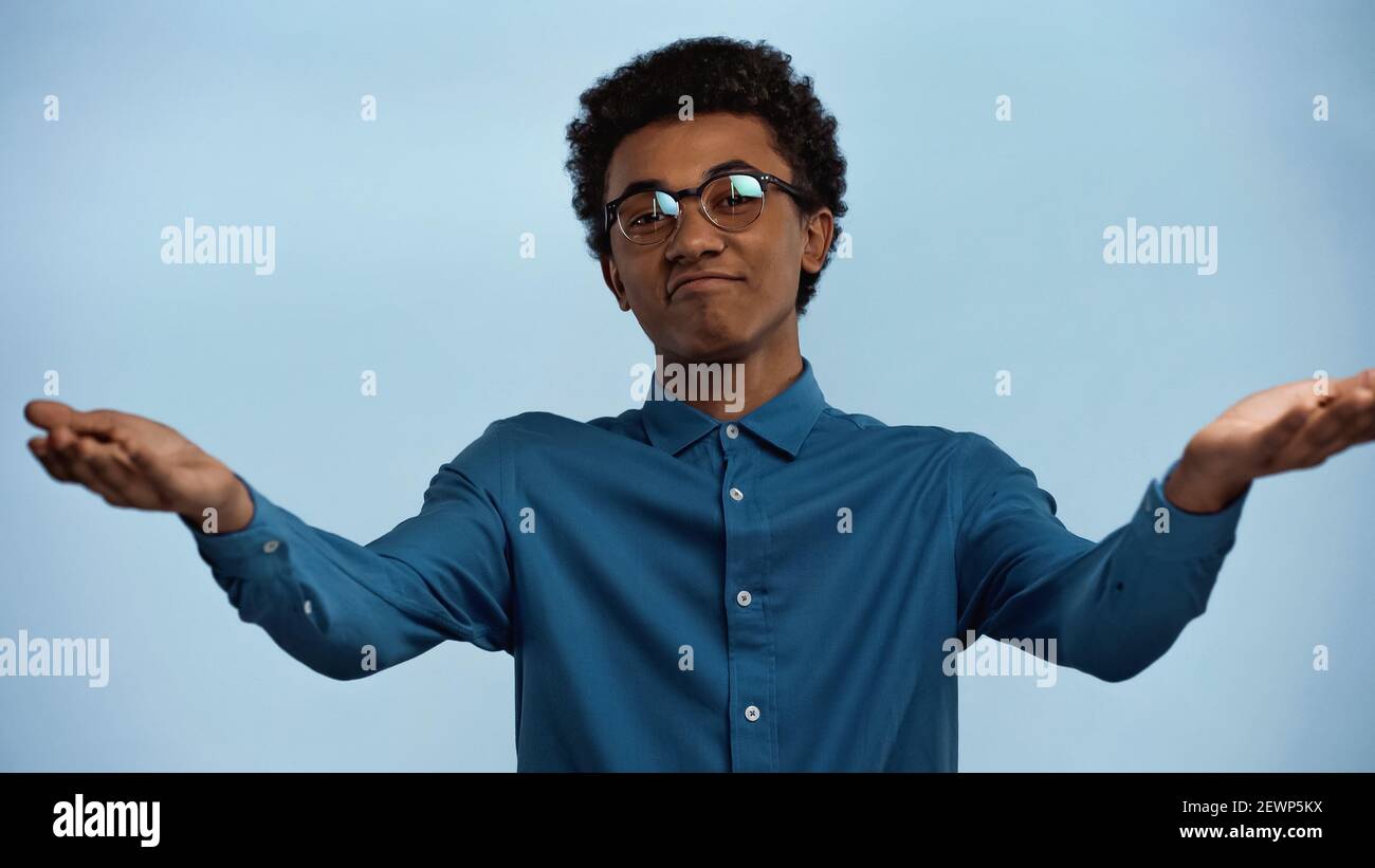 african american teenage boy showing shrug gesture isolated on blue ...