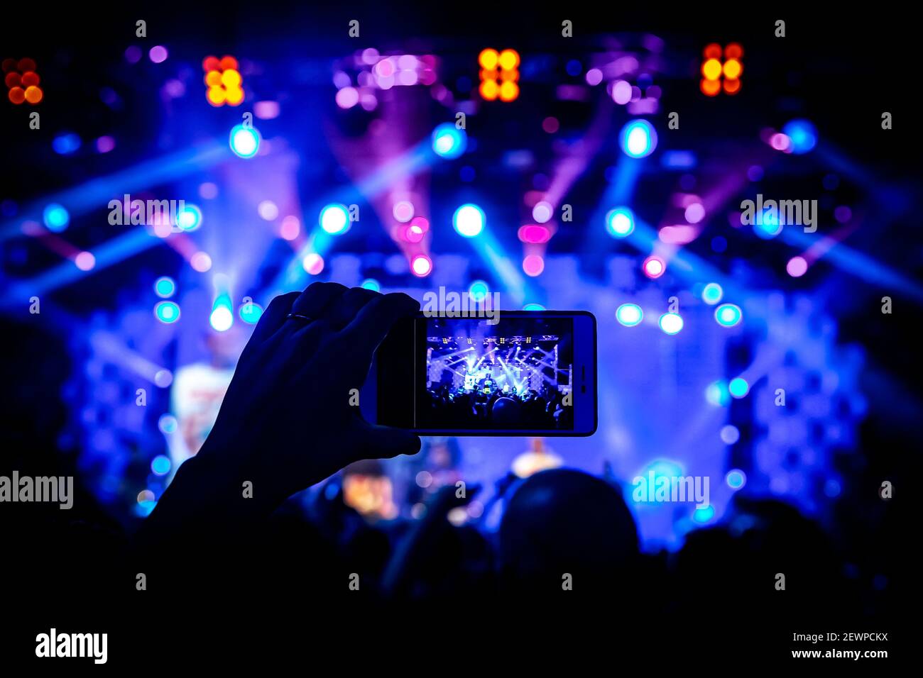 Man takes a picture of the show at the concert hall using a smartphone ...