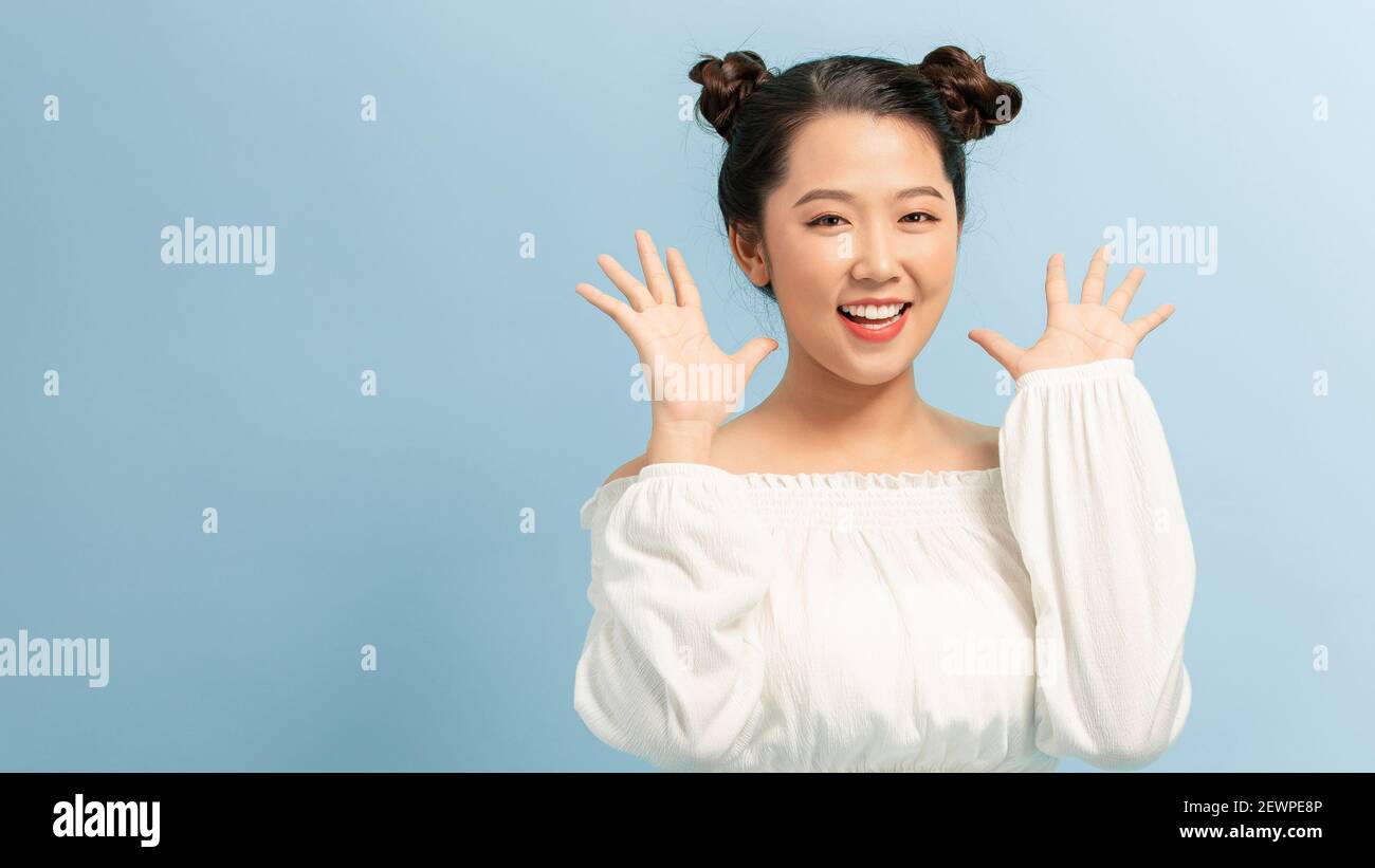 Surprised young woman shouting over blue background. Looking at camera ...