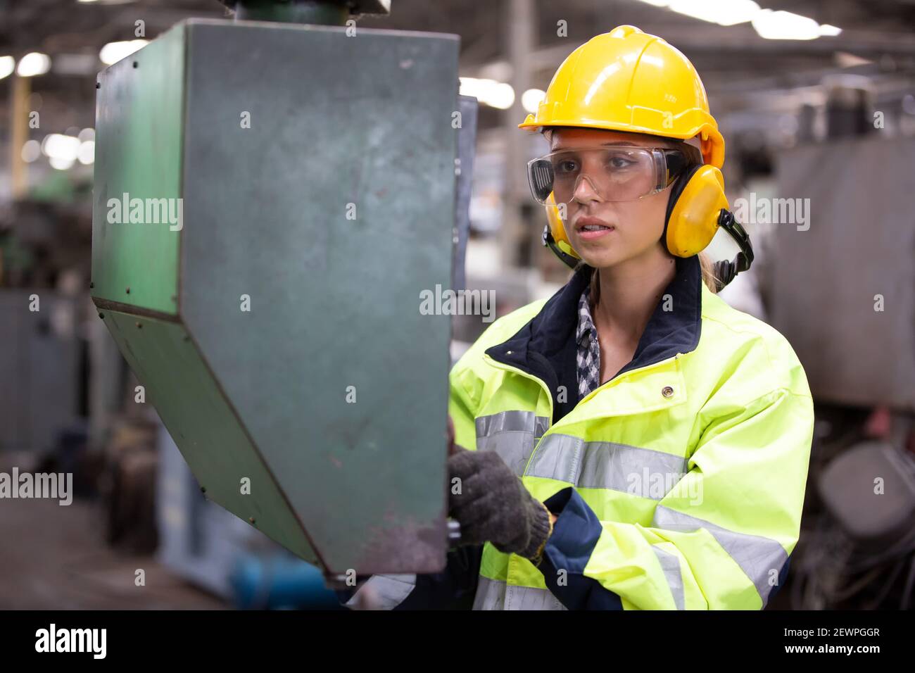 Woman worker wearing safety goggles control lathe machine to drill ...