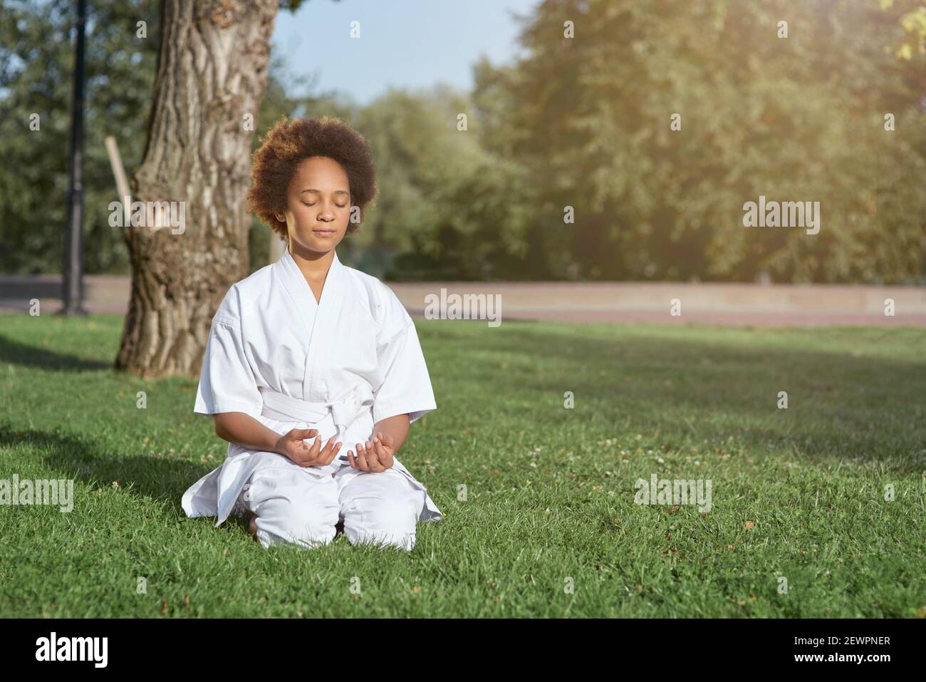 Adorable little girl in karate kimono meditating outdoors Stock Photo ...