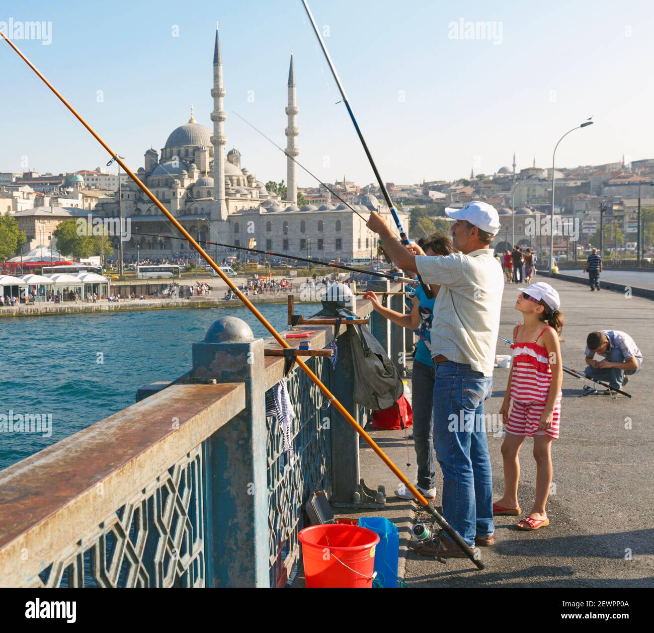 Istanbul, Turkey. Family fishing from the Galata Bridge. The New Mosque ...