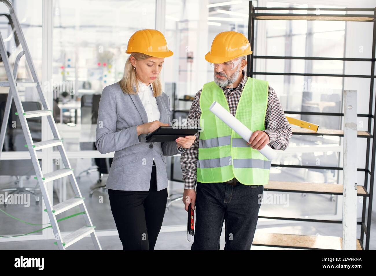 Designer and contractor in helmets standing on construction Stock Photo ...