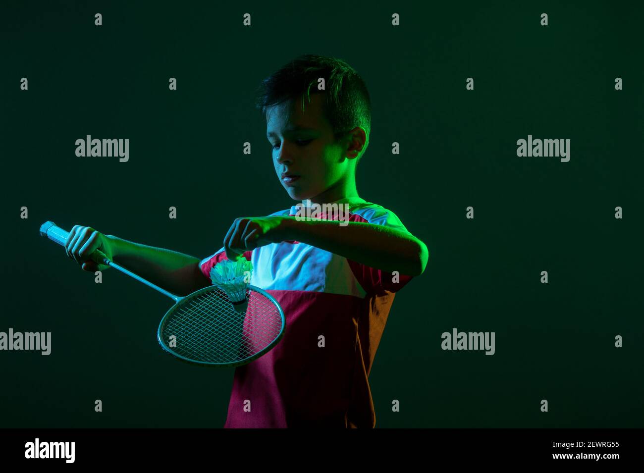 Kid playing badminton isolated on black background in mixed light. Blue ...