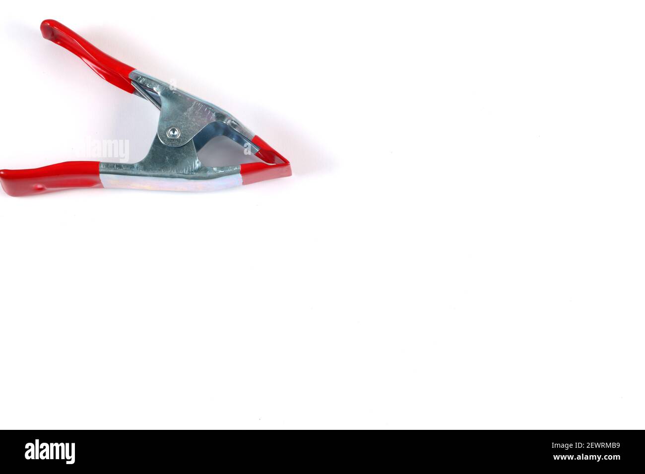 A metal spring clamp with red plastic handles and tip isolated on white ...