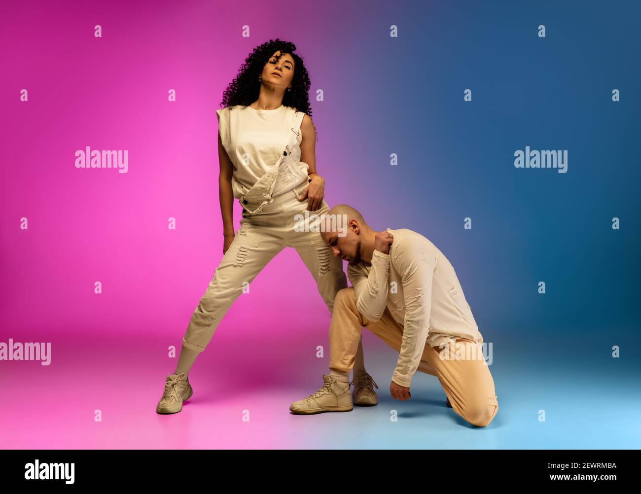 Stylish sportive caucasian couple dancing hip-hop on colorful gradient ...
