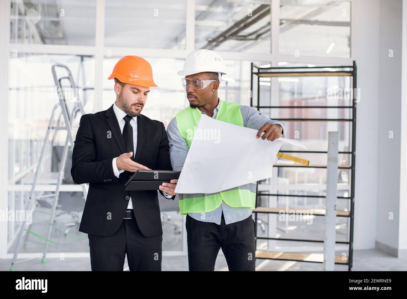 Group of two multi ethnic men inspecting industrial plan Stock Photo ...