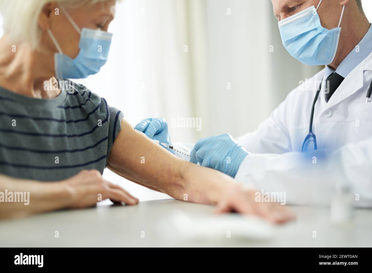 Doctor in sterile gloves injecting vaccine into patient arm Stock Photo - Alamy