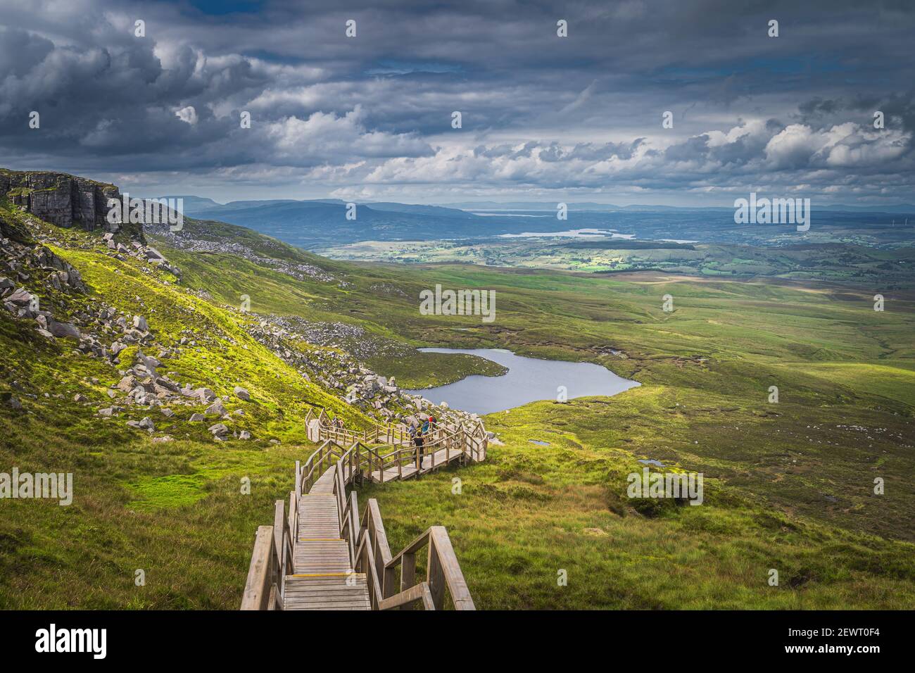 People hiking on steep stairs of wooden boardwalk in Cuilcagh Mountain ...
