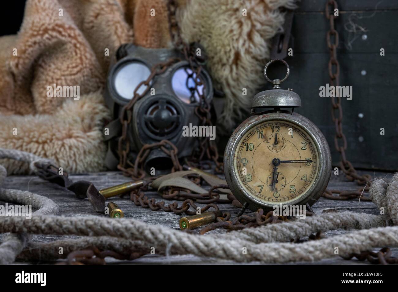 Vintage clock resting on wooden surface with military gas mask and ...