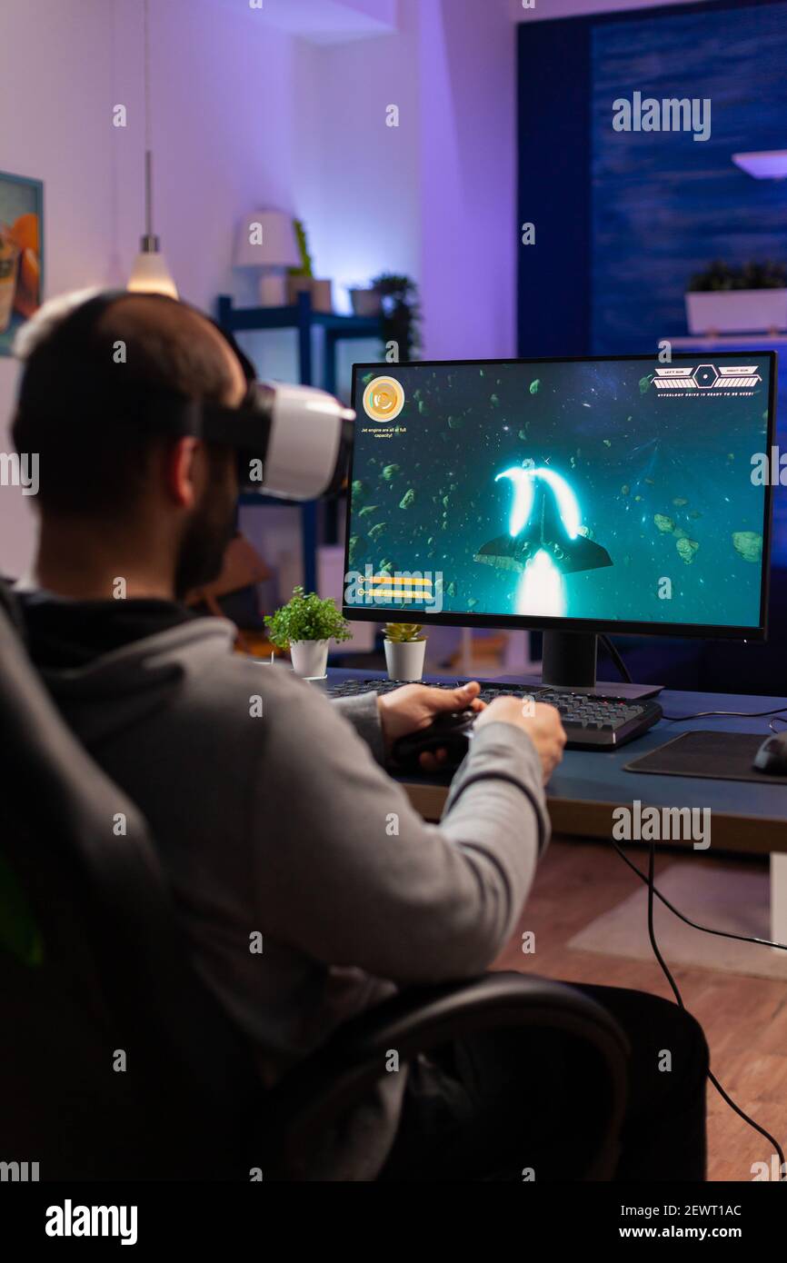 Player man playing video game at powerful computer late night wearing ...