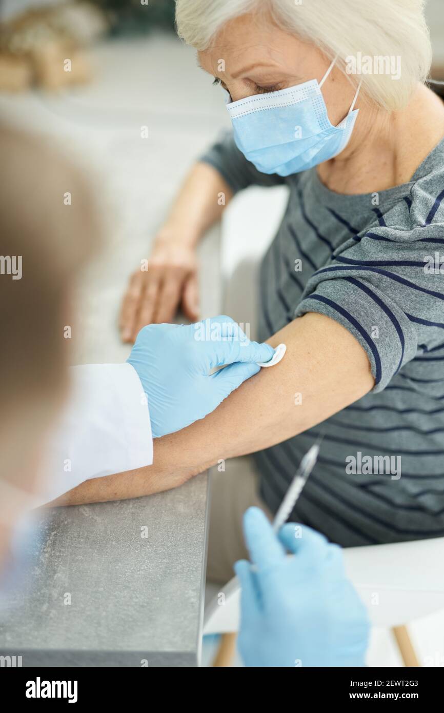 Doctor cleaning old woman skin with alcohol swab before injection Stock ...