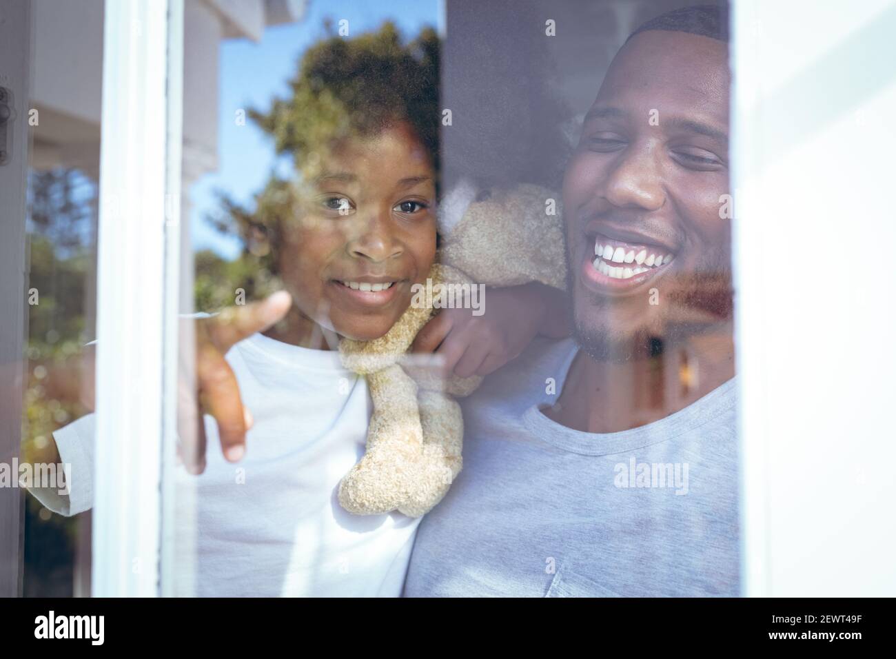 African american girl and her father holding teddy bear looking through ...