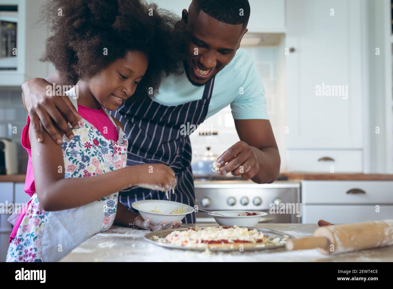 African american girl and her father making pizza together in kitchen ...