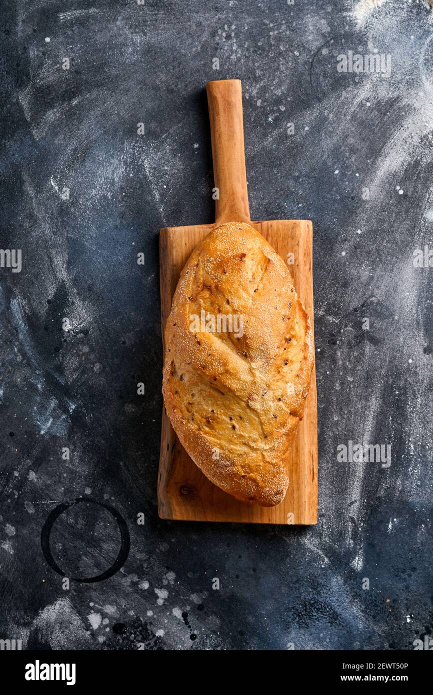 Homemade bread with seeds on a wooden stand, wheat flour and ears on ...