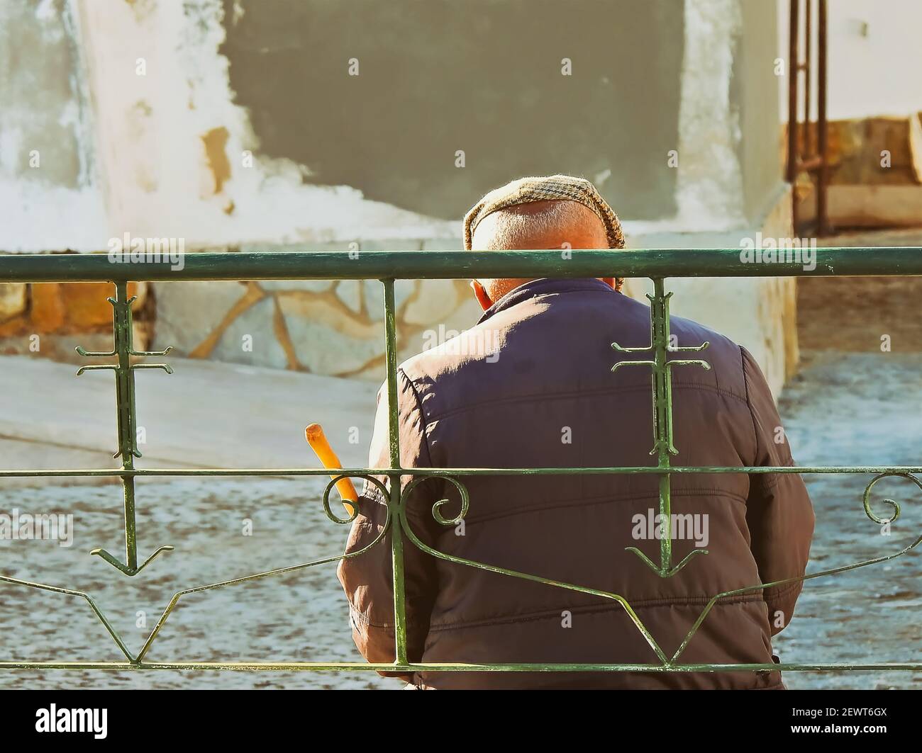 An old man sitting beside the metal railings outside a church Stock ...